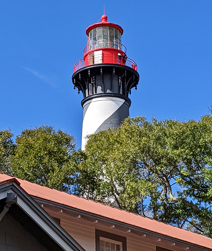 The St. Augustine Lighthouse's bold red cap and spiraling stripes have guided mariners home since 1874, a candy-striped sentinel against the azure sky.