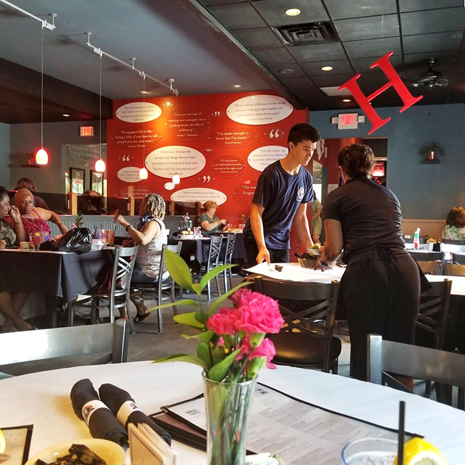 A vibrant red wall showcases inspirational quotes while diners and staff create their own memorable moments. Fresh flowers on each table&mdash;a small touch that speaks volumes.