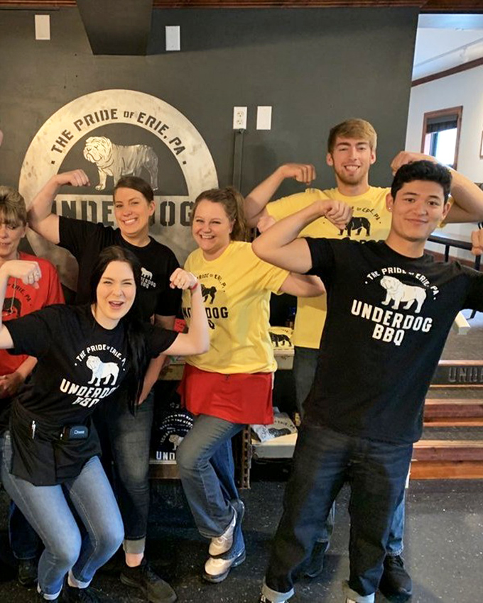 The enthusiastic team flexes their "barbecue muscles," embodying the pride of Erie with smiles as warm as their slow-smoked specialties.