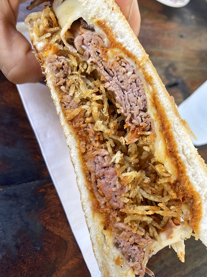 The Pan con Bistec reveals its secrets: tender steak, crispy potato sticks, and melted cheese in perfect harmony. Worth crossing state lines for.