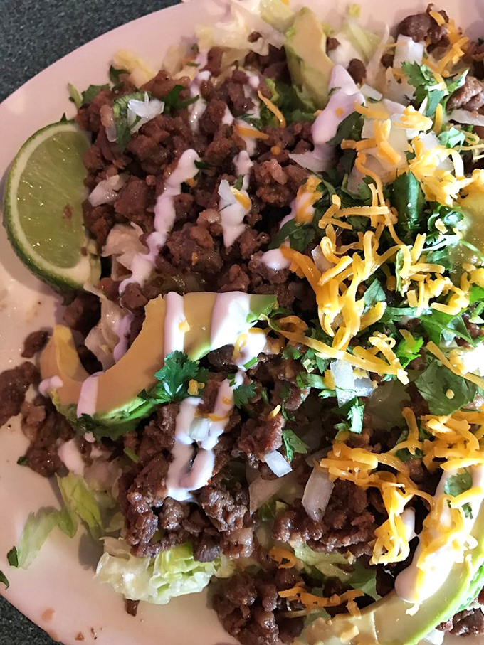 A taco salad that refuses to hide in a fried tortilla bowl, instead proudly displaying its bounty of seasoned meat, fresh vegetables, and creamy drizzle.
