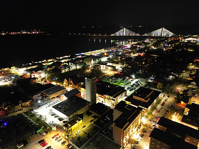As night falls, Cape Girardeau's lights twinkle along the riverfront, with the illuminated bridge creating a magical gateway between states.