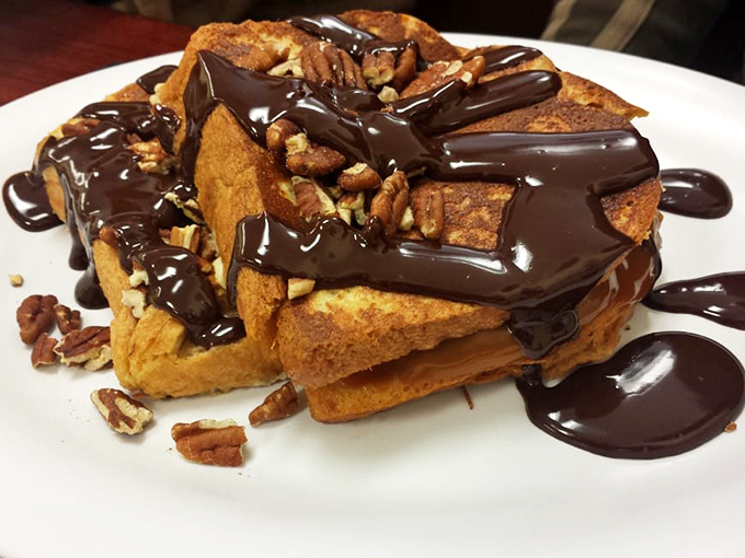 French toast that's crossed the line from breakfast to dessert and isn't apologizing for it. Those pecans and chocolate drizzle are living their best life. 