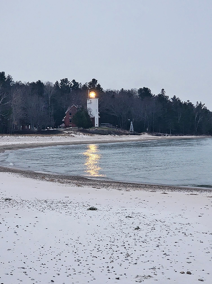 Winter transforms the lighthouse into a snow-globe scene, with its light creating a golden path across the icy waters of Lake Huron.