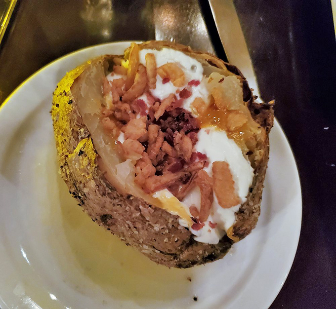 That loaded baked potato arrives like a fluffy canvas painted with bacon, cheese, and pure indulgence dreams.