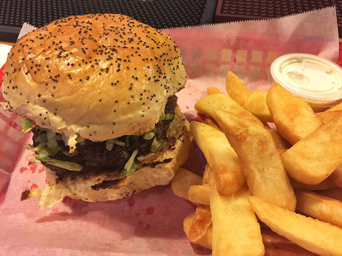 This isn't just a burger; it's an architectural achievement &ndash; layers of flavor stacked high on a poppy seed bun with fries standing by for backup.
