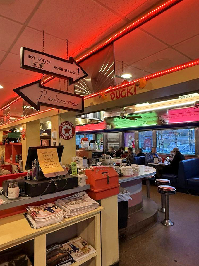Those directional signs aren't just functional&mdash;they're diner poetry pointing you toward the essentials: hot coffee, fresh service, and yes, the restrooms.