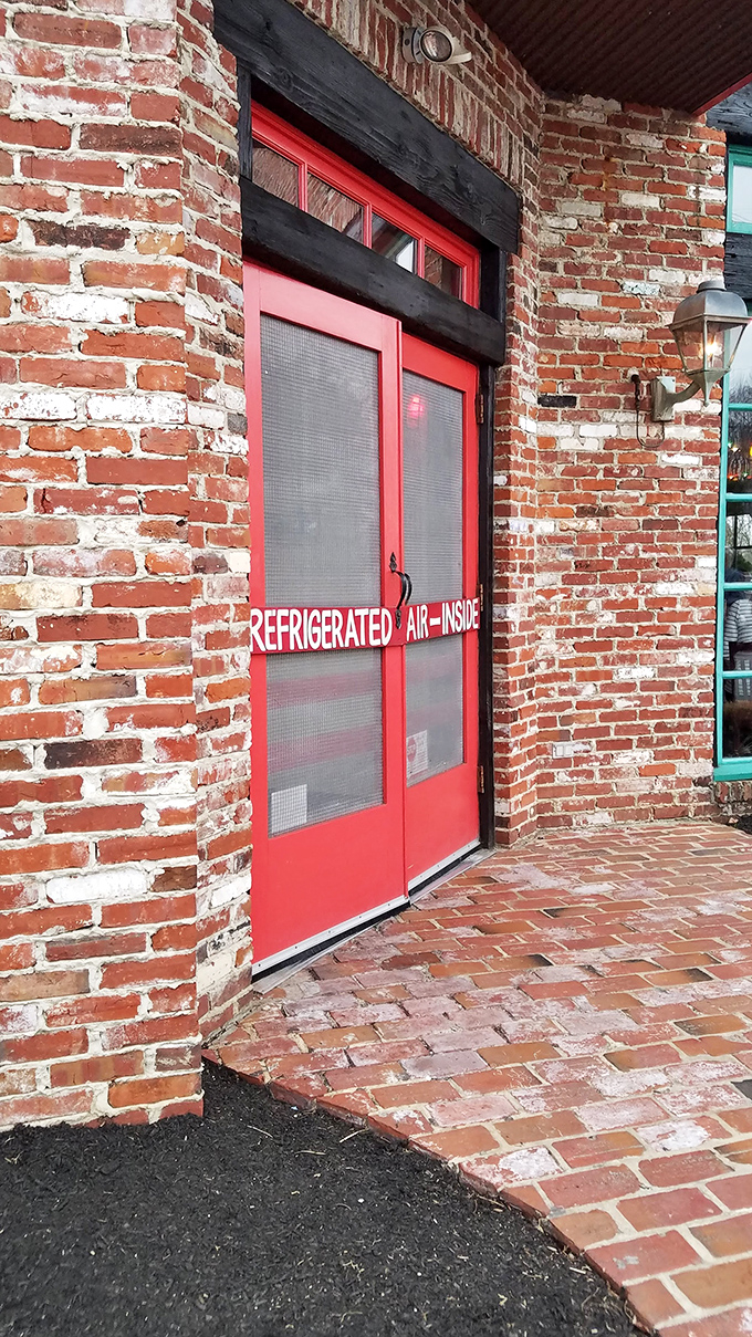 The red door promises "REFRIGERATED AIR INSIDE" &ndash; and who are we to argue with such straightforward hospitality? The brick exterior adds rustic charm.