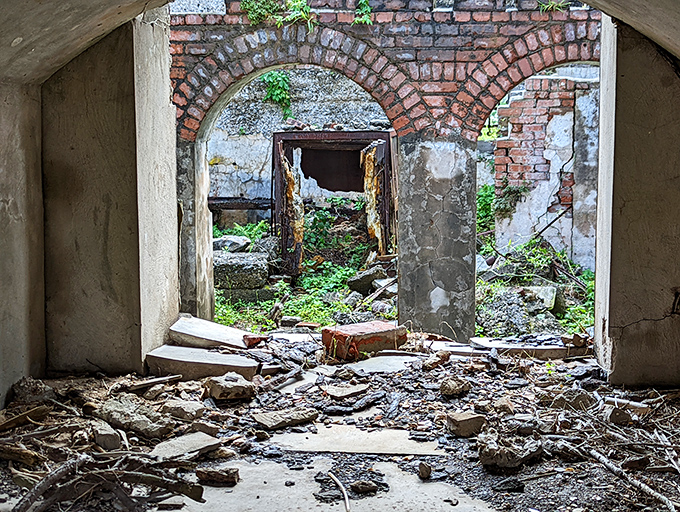 Peering through crumbling doorways reveals nature's slow reclamation project—brick arches frame views of what was once opulent interior space.