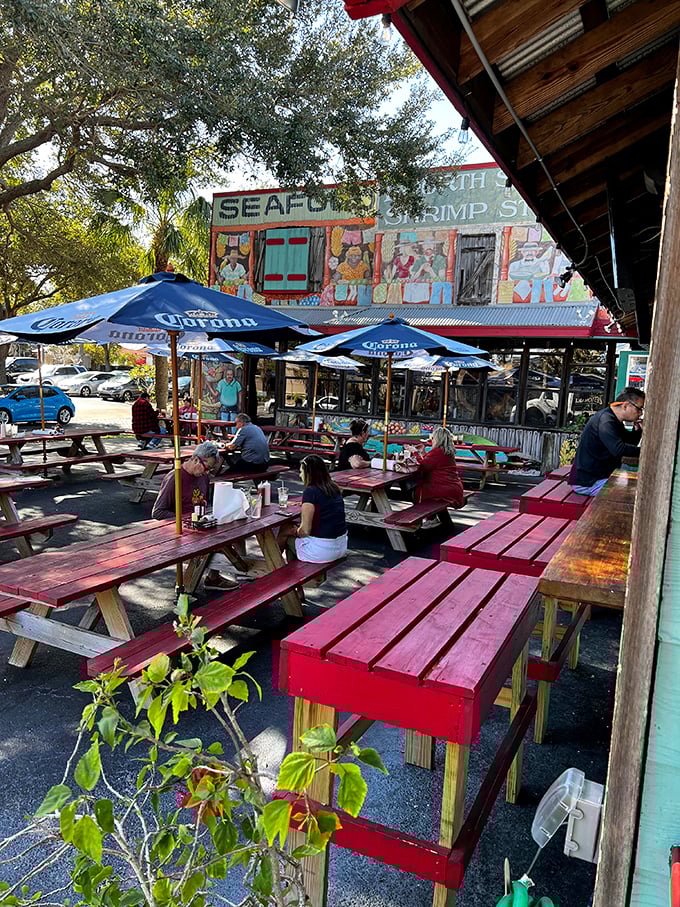 Red picnic tables under blue umbrellas—where outdoor dining feels less like a restaurant and more like the best backyard party in town.