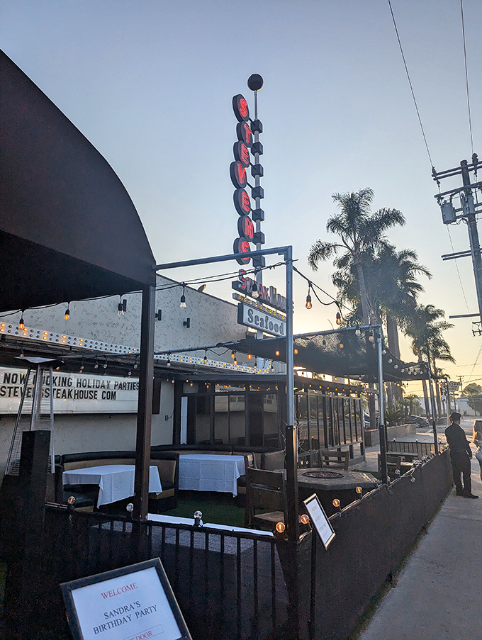 The vertical neon sign stands tall against the California sky, a mid-century beacon that's been guiding hungry pilgrims to beef paradise for generations.