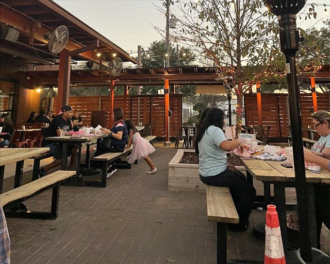 The outdoor dining area offers a perfect Texas evening experience—casual picnic tables, string lights, and the promise of burger bliss.