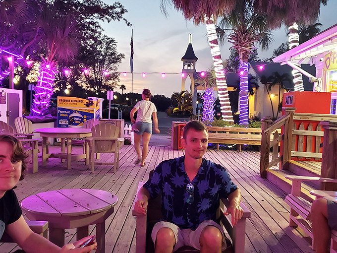Twilight transforms the porch into a purple-hued dining paradise. These aren't just outdoor tables &ndash; they're front-row seats to island magic. 