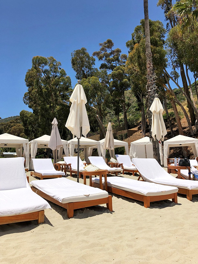 Beach loungers await under pristine white umbrellas, practically begging you to recline with a good book and bad intentions toward your work email.