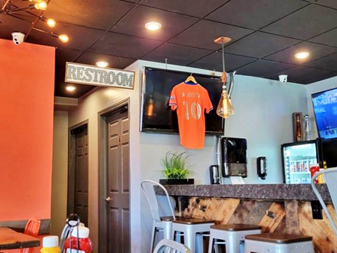 Even the path to the restroom maintains the orange-accented theme, proving that thoughtful design extends to every corner of this burger haven.