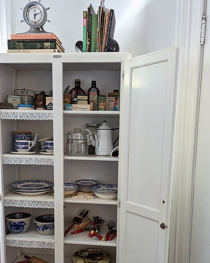 A pristine cabinet revealing the blue-and-white dishes that have graced American homes for generations. Those doilies weren't optional in proper households.