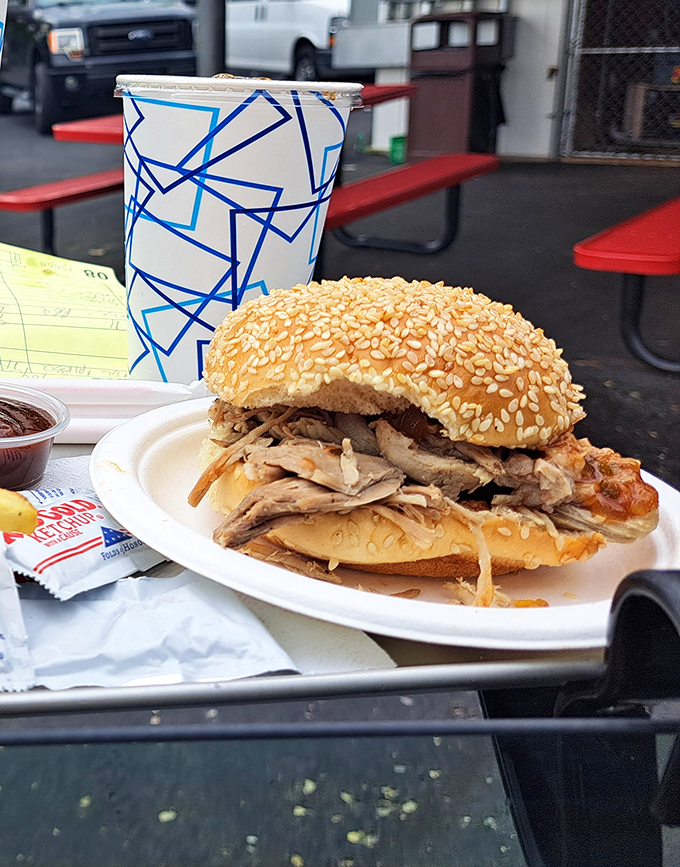 The BBQ sandwich that launched a thousand road trips—tender meat piled high on a sesame bun, sitting pretty beside its blue-patterned cup companion.