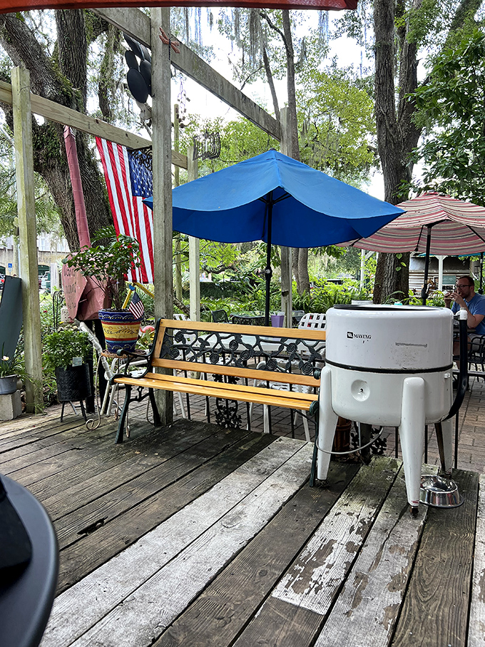 Old-school wooden benches and colorful umbrellas create the perfect spot for post-sandwich contemplation under ancient oak trees.