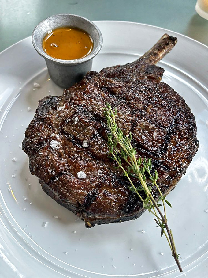 The bone-in ribeye arrives like a primal masterpiece&mdash;perfectly charred outside, juicy inside, with a side of sauce you'll definitely be dipping into.