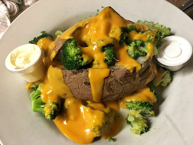 A loaded baked potato that's dressed better than most people at formal events. That river of cheese sauce makes broccoli an actual temptation.