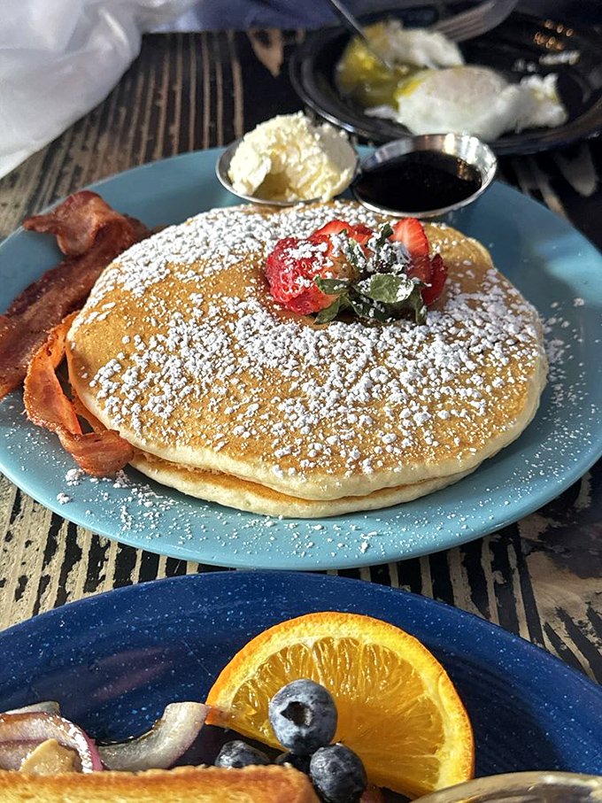 Buttermilk pancakes that achieve the impossible: cloud-like fluffiness with perfectly crisp edges, dusted with powdered sugar and topped with fresh berries.