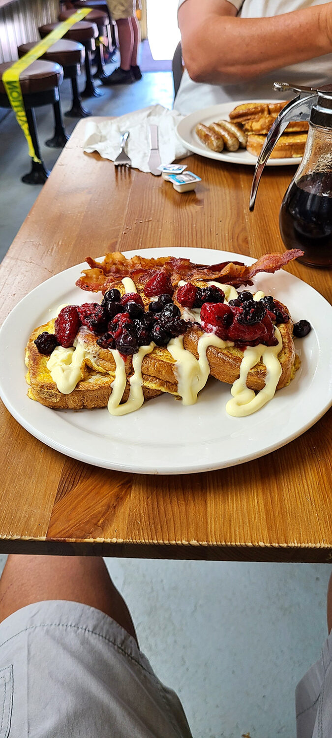 Breakfast that's dressed for dessert. French toast topped with berries, cream, and a side of bacon proves that balance is everything in life.