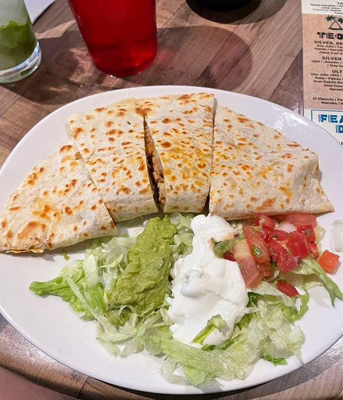 The humble quesadilla, elevated to art form. Golden-brown exterior giving way to melty goodness inside, with the holy trinity of toppings standing by.