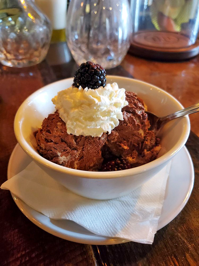 A chocolate dessert that deserves its own slow-motion montage, topped with a blackberry that's basically wearing a tiny crown.