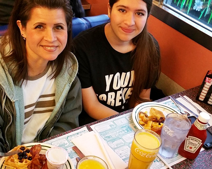 The image shows diners enjoying their meal in the restaurant's comfortable booth seating, with breakfast plates and beverages creating a classic American dining scene.