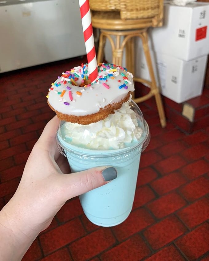 Not just a milkshake but a structural engineering marvel, crowned with a donut hat and candy cane straw for maximum joy delivery.