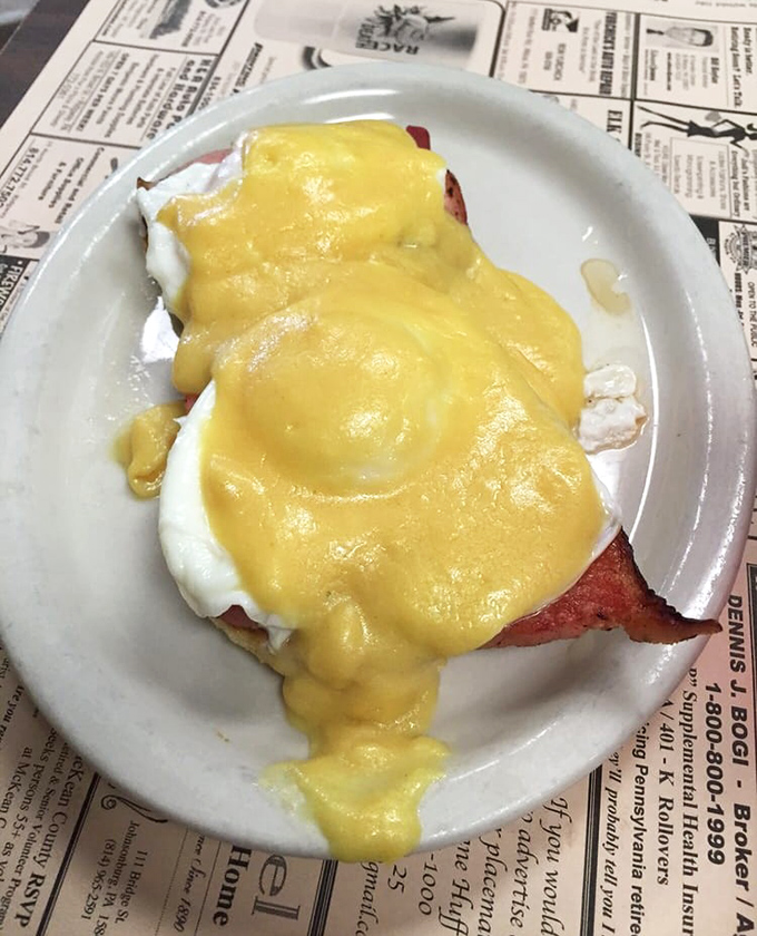 Hollandaise river flowing over Canadian bacon islands. This Benedict isn't just breakfast—it's morning luxury on a humble diner plate.