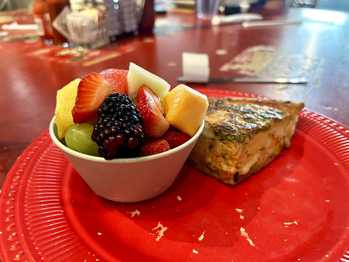 A perfect quiche slice beside a cup of fresh fruit&mdash;proof that breakfast can be both virtuous and indulgent in the very same bite. 