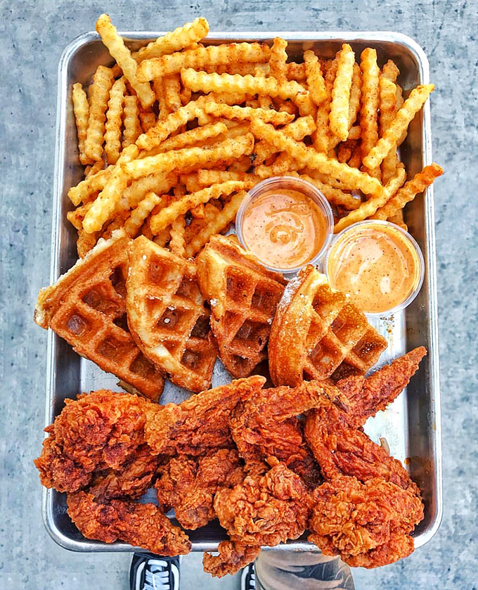 The ultimate trifecta: crispy chicken, golden waffles, and perfect fries. Not a meal, but a monument to comfort food perfection.