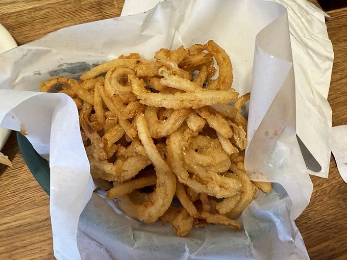 Onion rings so perfectly crisp and abundant they spill from their paper nest like golden treasure from a pirate's chest.