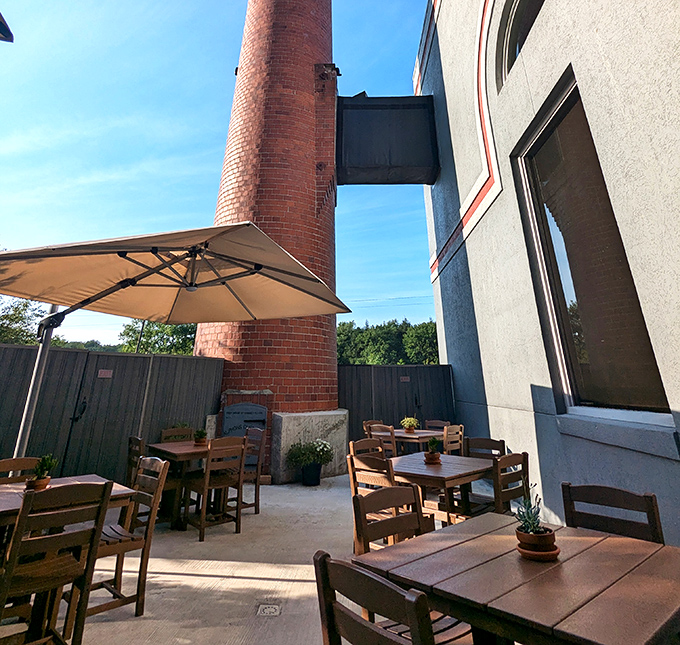 The outdoor patio nestled against that magnificent brick smokestack offers al fresco dining with industrial-age character.