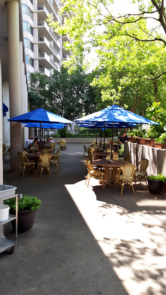 The outdoor seating area&mdash;a perfect urban oasis where blue umbrellas provide shade for conversations that stretch from brunch well into the afternoon.