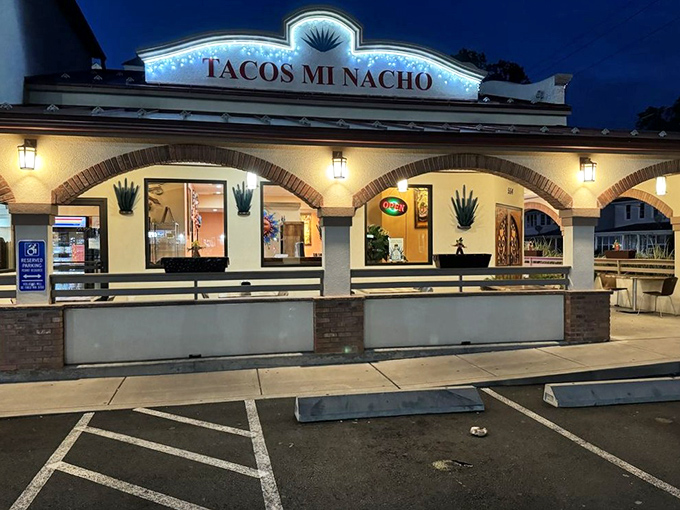 As evening falls, Tacos Mi Nacho glows with invitation, its illuminated sign promising a fiesta of flavors just steps away from your car.