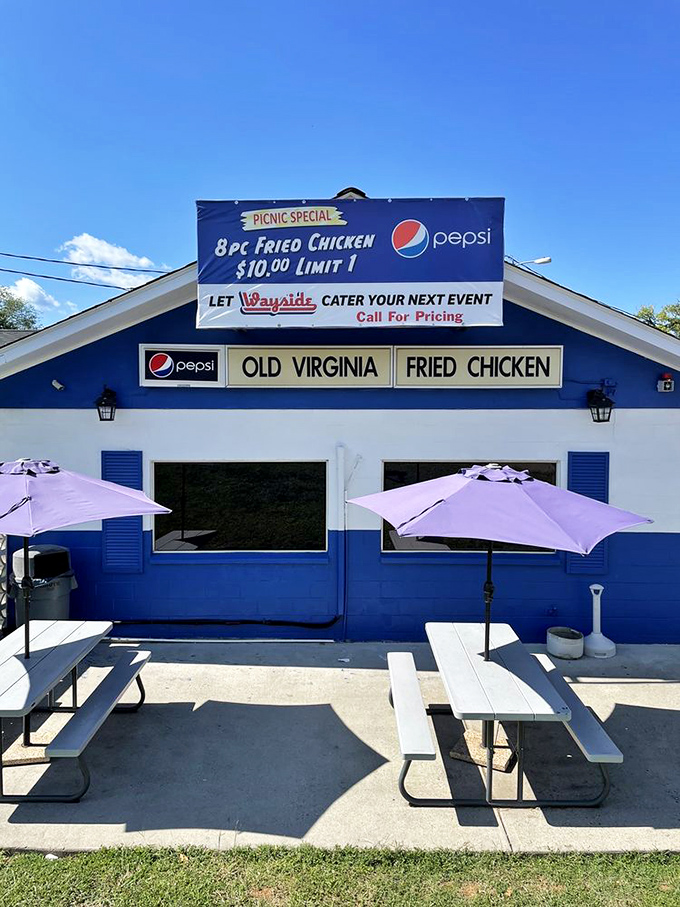 Outdoor picnic tables under purple umbrellas invite you to sit and enjoy a budget-friendly meal of delicious southern fried chicken.