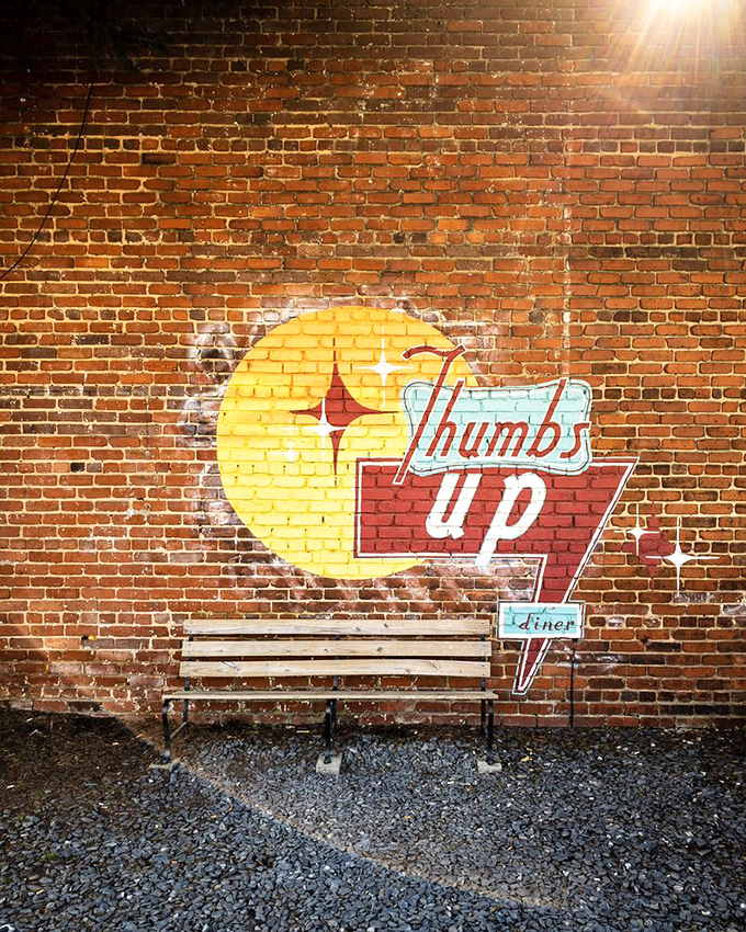 The iconic Thumbs Up sign painted on brick serves as a beacon for breakfast seekers. Many a morning craving has ended happily on this bench.