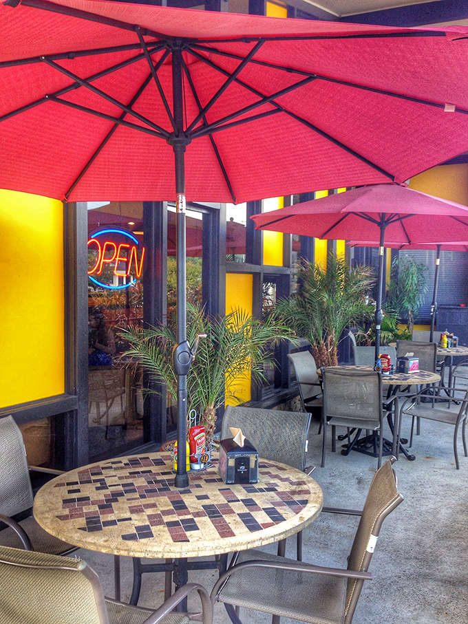 Red umbrellas create islands of shade where outdoor diners can enjoy their treasures while watching the world rush by to lesser meals.