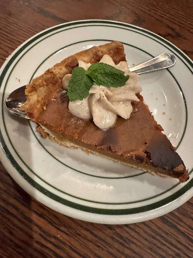 A slice of pie that demands respect and a dollop of whipped cream. That mint leaf isn't just garnish&mdash;it's a tiny green crown.