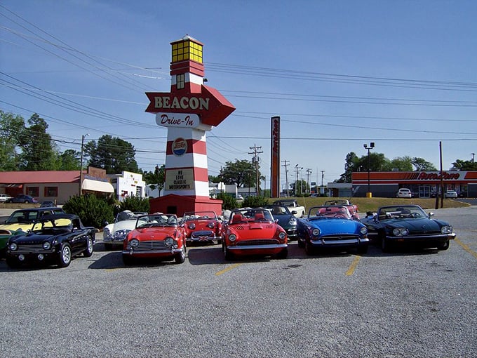 The lighthouse-inspired sign stands tall above vintage cars, a beacon indeed for those seeking the intersection of nostalgia and really good eating.