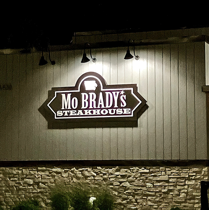 The illuminated sign against the stone and wood exterior serves as a beacon for hungry travelers. Follow the light to flavor town.