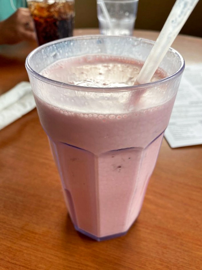 A strawberry milkshake so thick your straw stands at attention, delivering creamy, berry-infused happiness with each determined sip.