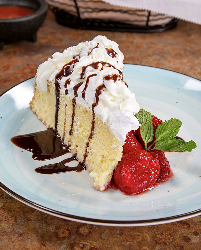 Tres Leches cake that looks like it's posing for a dessert calendar – moist, milk-soaked perfection with whipped cream, chocolate drizzle, and fresh berries.