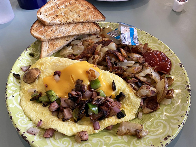 An omelet that's been properly introduced to cheese, with home fries that have achieved the perfect crisp-to-tender ratio. Toast stands by, ready for action. 