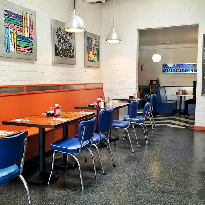 Orange walls and blue chairs create a visual pop that matches the flavor explosions on your plate. Art on the walls, art on your fork.