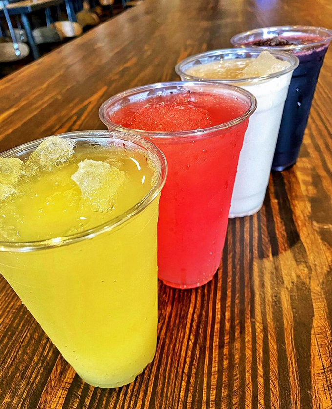 Colorful agua frescas lined up like liquid rainbows, offering the perfect sweet relief between bites of spicy perfection. 