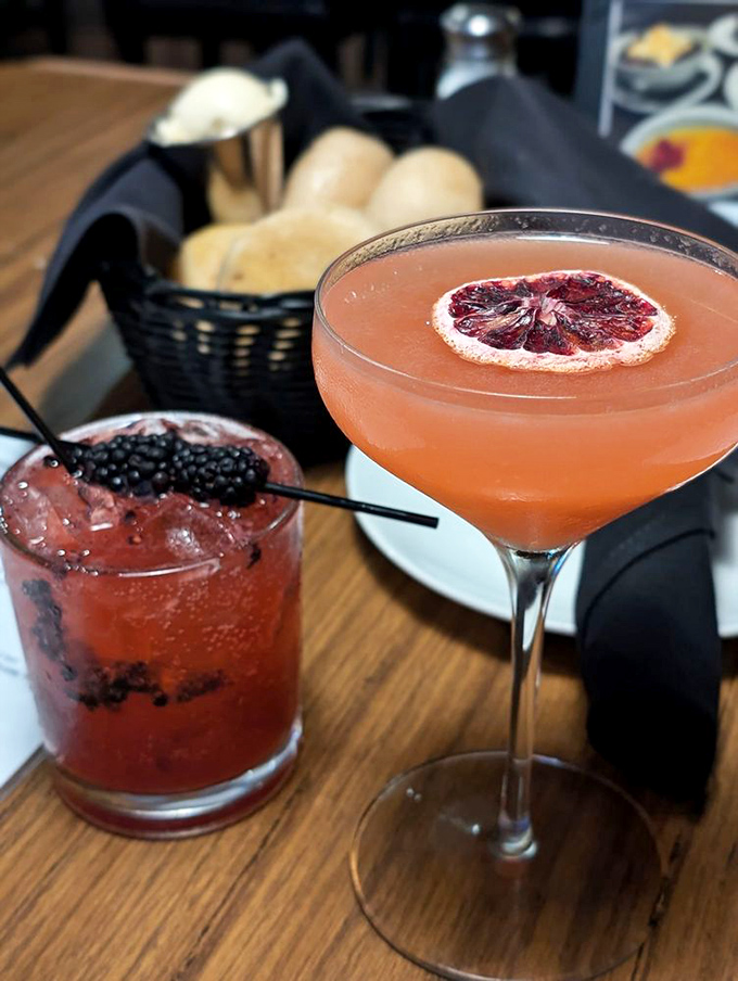 Craft cocktails that look like liquid sunset, garnished with blood orange and blackberries. Proof that what accompanies your steak deserves equal billing.