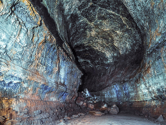 Inside the cave, a kaleidoscope of colors emerges under proper lighting. The seemingly monochrome walls reveal surprising blues, reds, and golds &ndash; nature's hidden art gallery beneath Central Oregon.